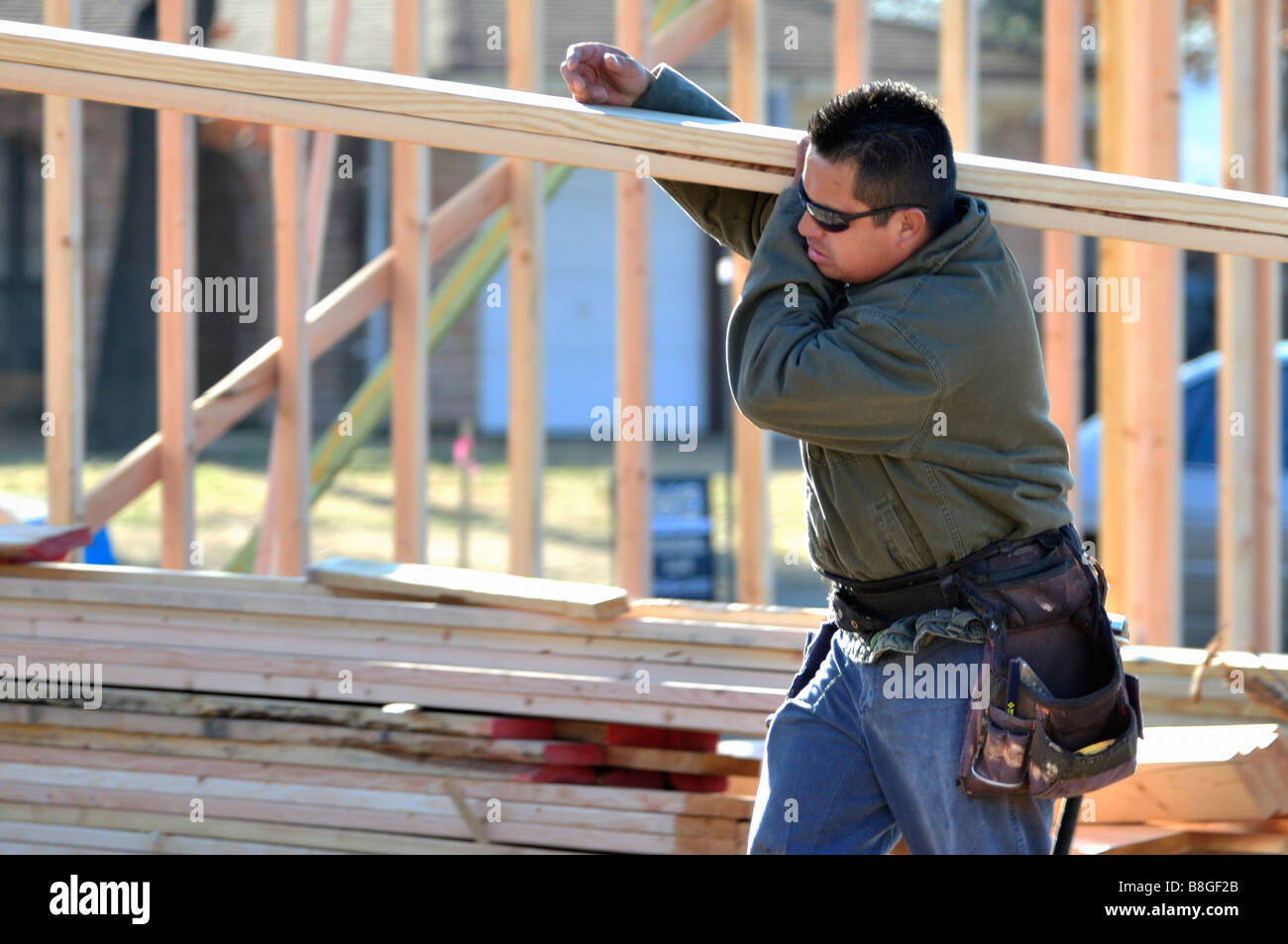 A Hispanic workman carrying lumber while building a new house in ...