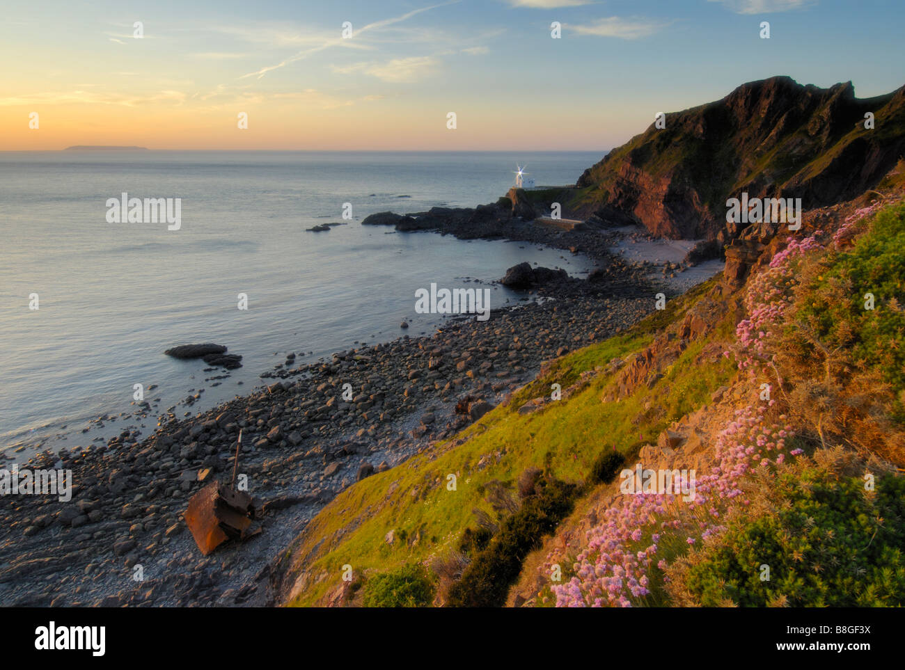 Hartland Point Lighthouse in the evening sun. On the beach is the bow ...