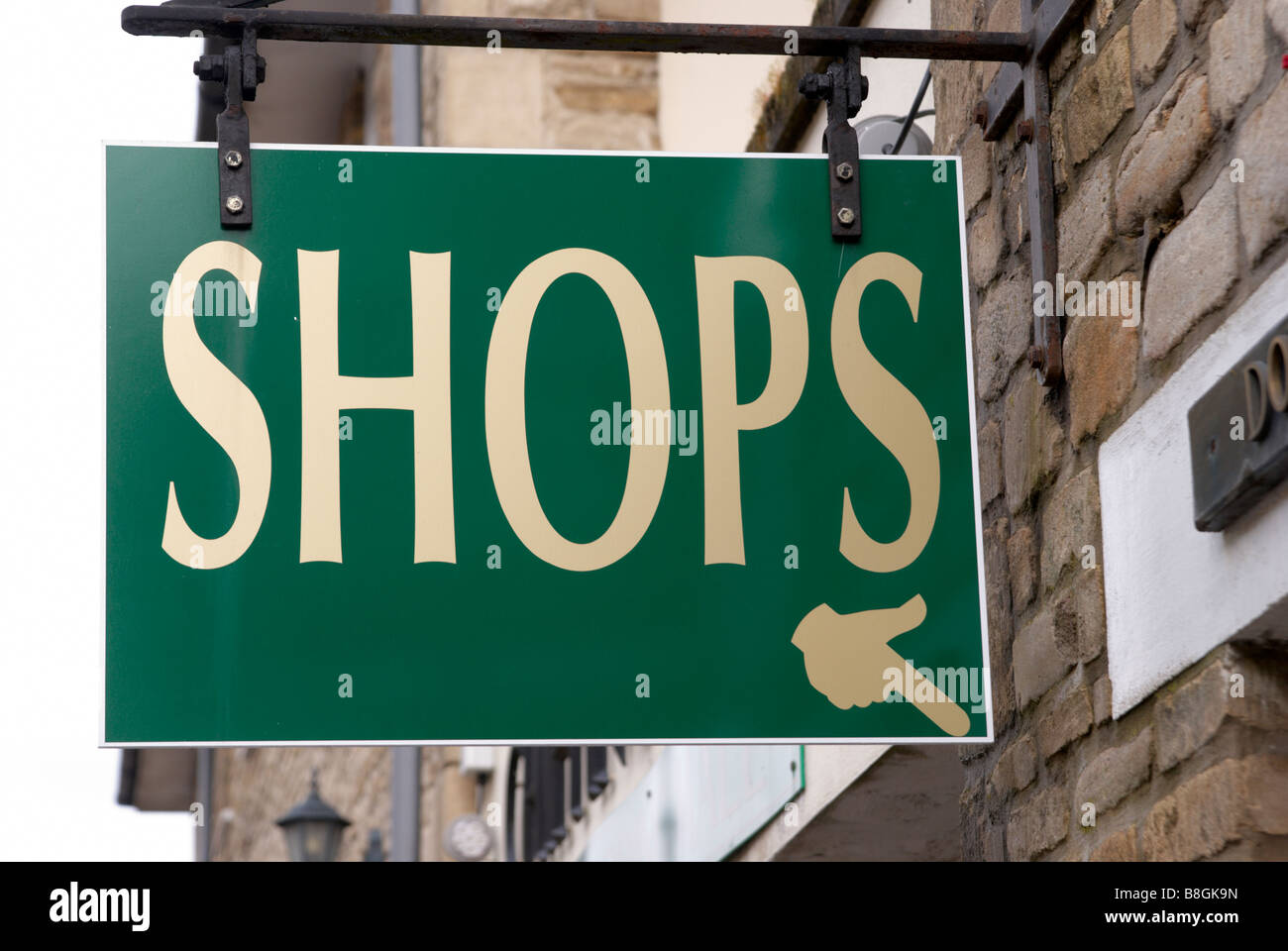 Green sign with word "shops" and pointing finger Stock Photo - Alamy