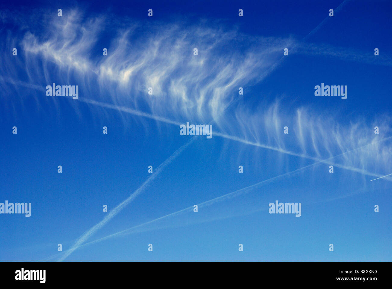 Aircraft trails cross in the sky Stock Photo - Alamy