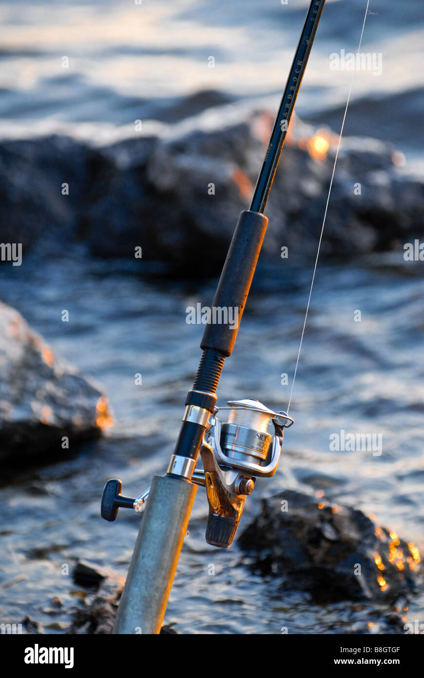 Lone fishing rod with rocks and water Stock Photo - Alamy