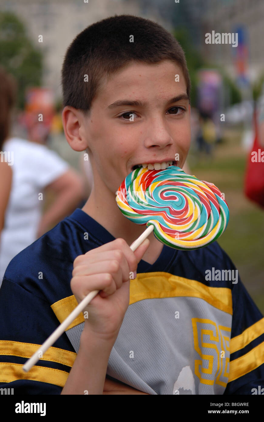 A young man taking a bit out of a large colourful lollipop Stock Photo ...