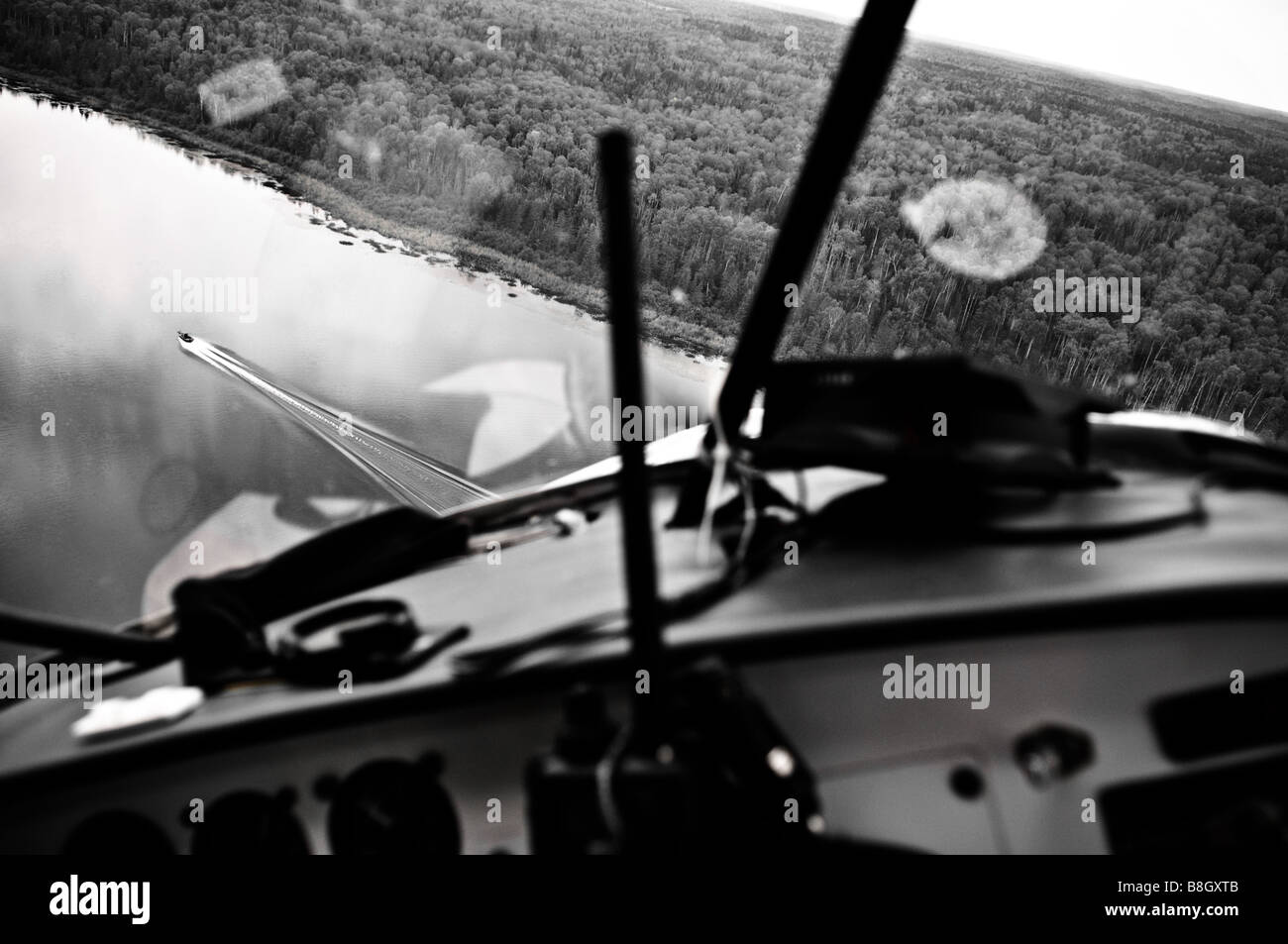 A small boat seen speeding along a river through an airplane cockpit ...