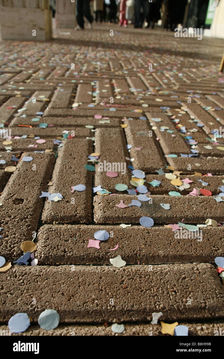 lots of colourful confetti and garlands on paved street road in sun ...