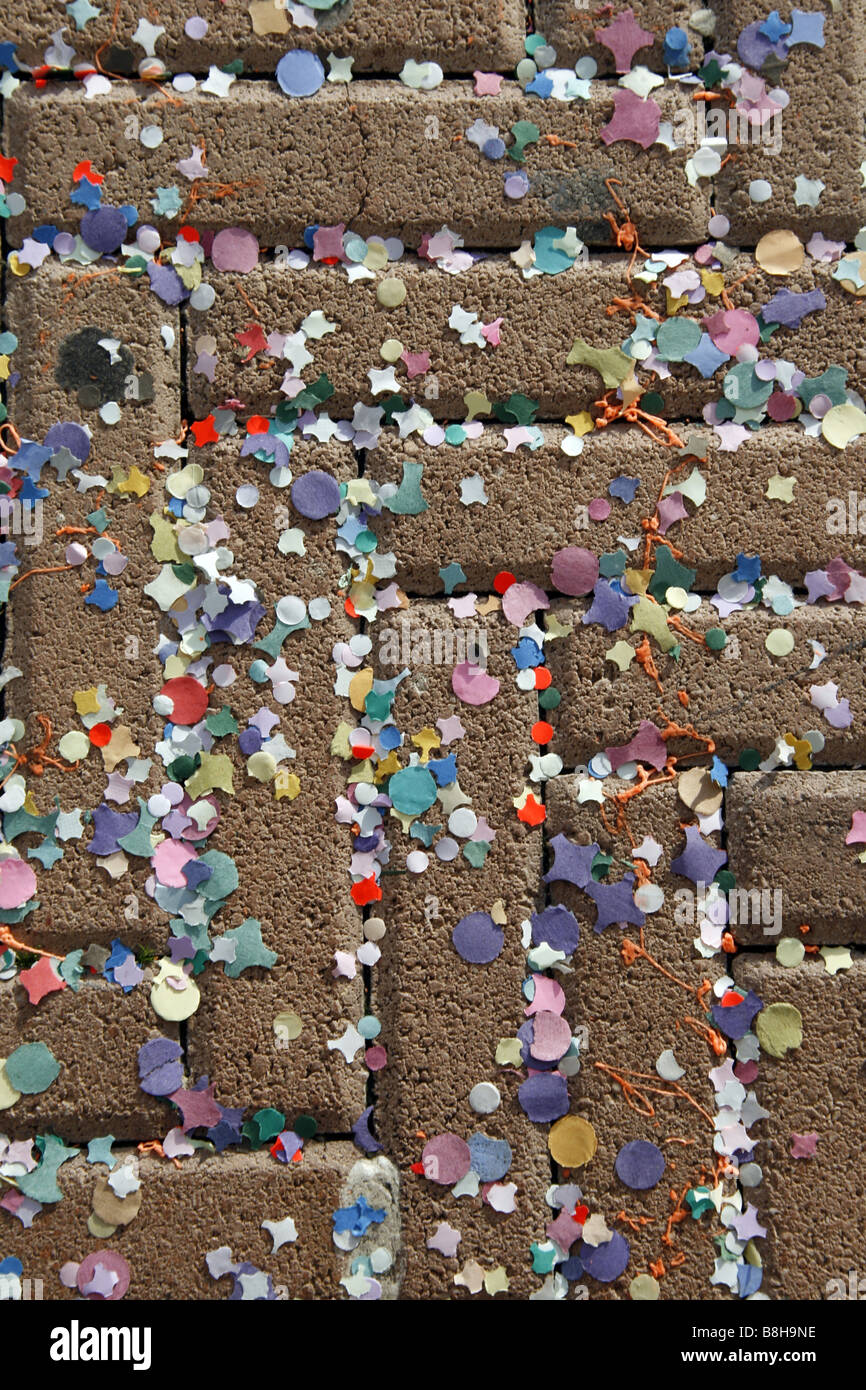 lots of colourful confetti and garlands on paved street road in sun ...