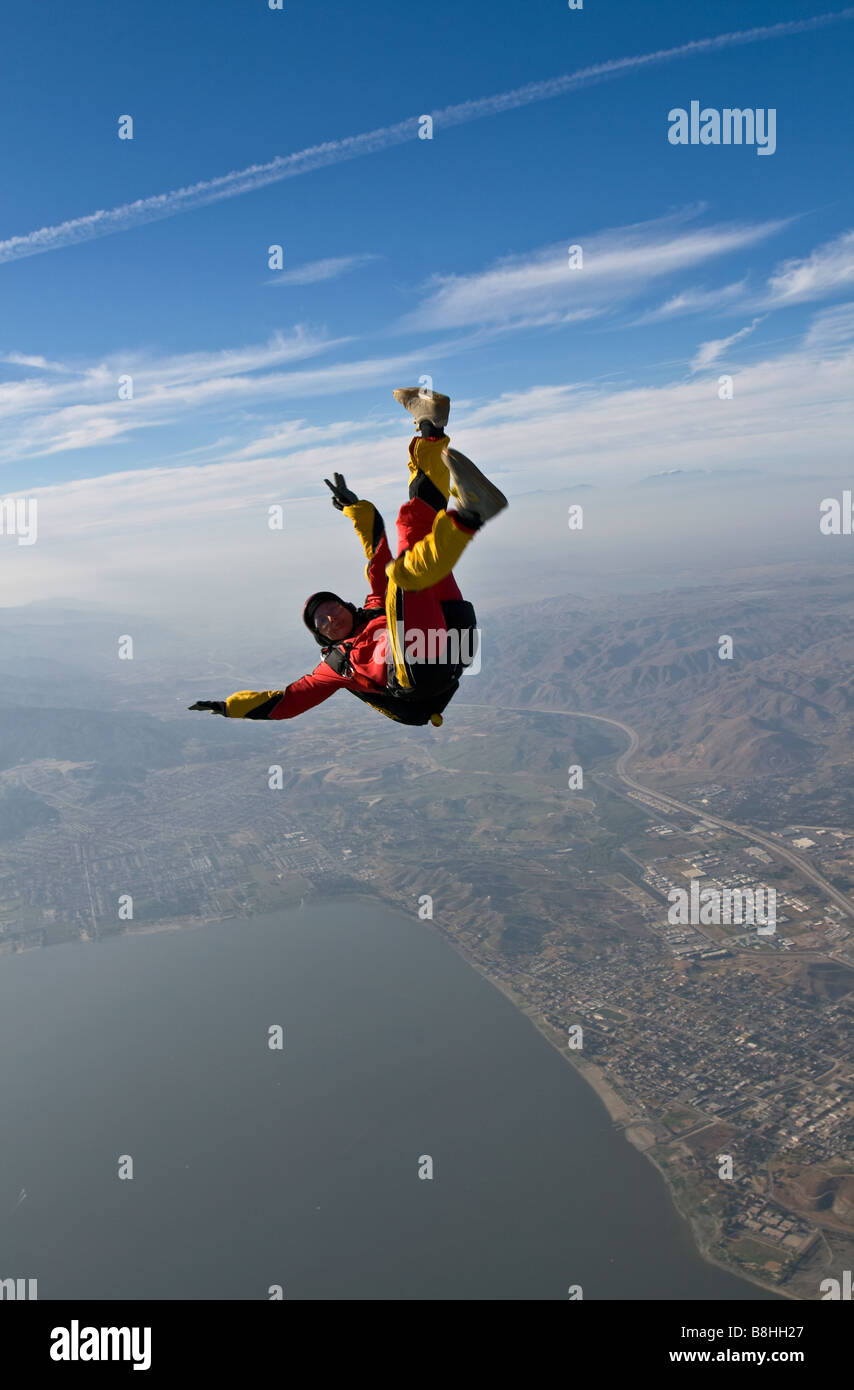 Skydiver is back flying in the blue sky over a big lake and having fun ...