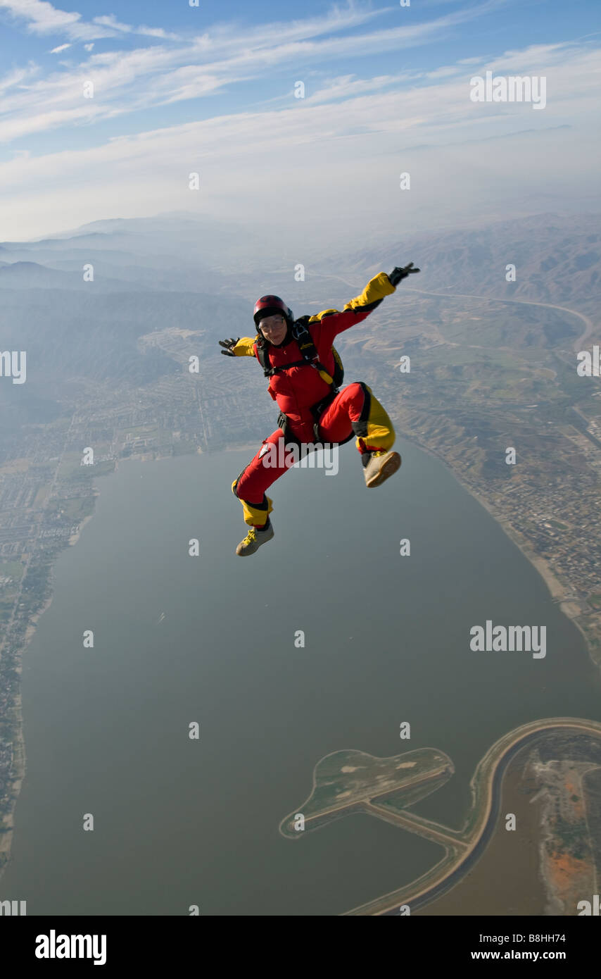 Skydiver is sit flying in the blue sky over a big lake and having fun ...