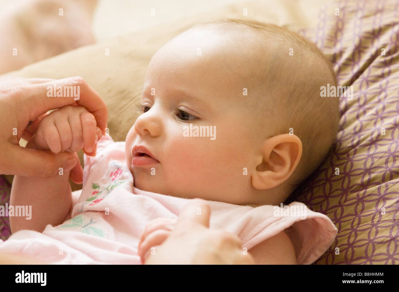 Baby concentrating on mothers hand Stock Photo - Alamy