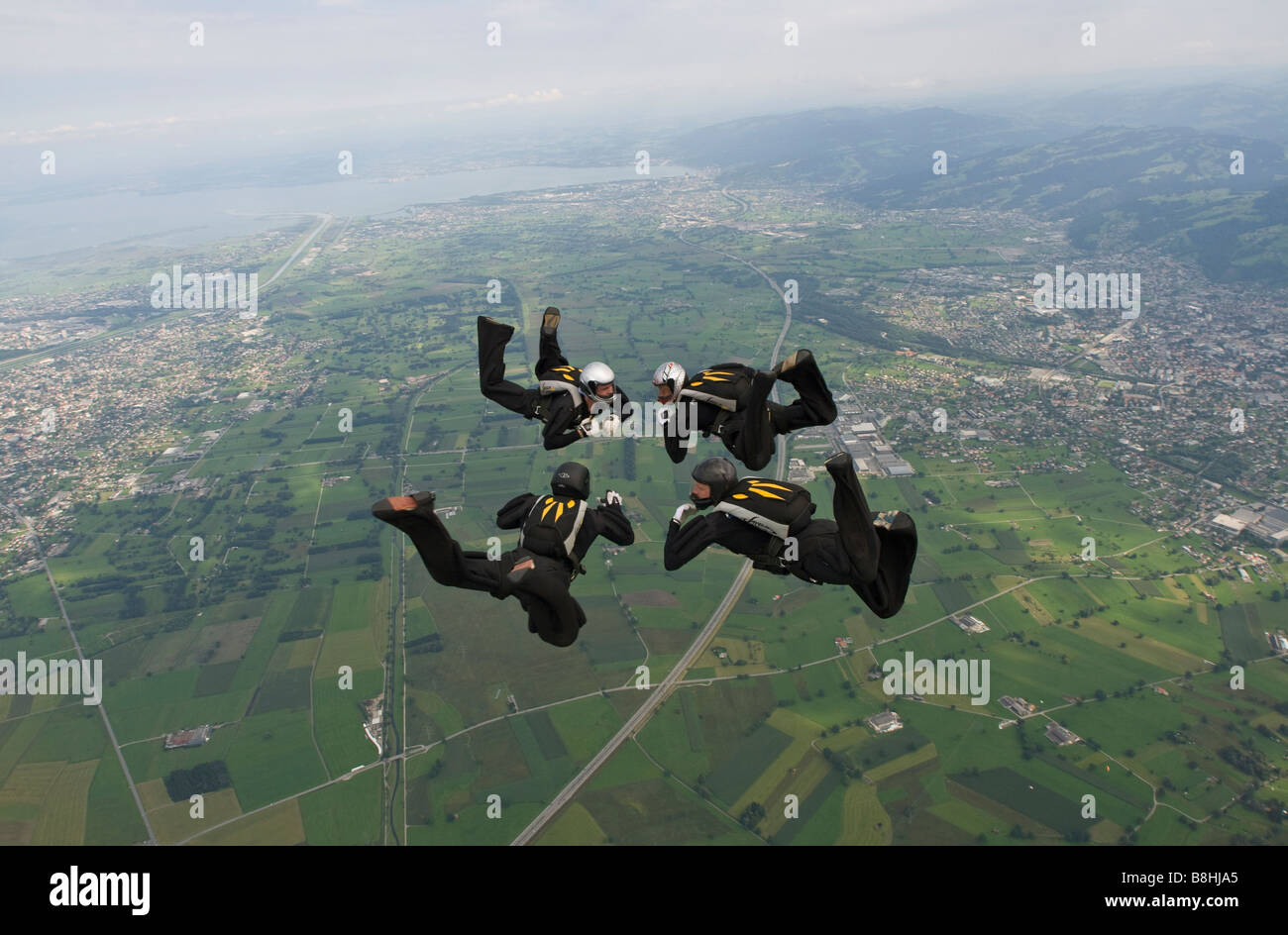 Skydiver team VIVA is flying a formation in the sky below clouds. 4-way ...