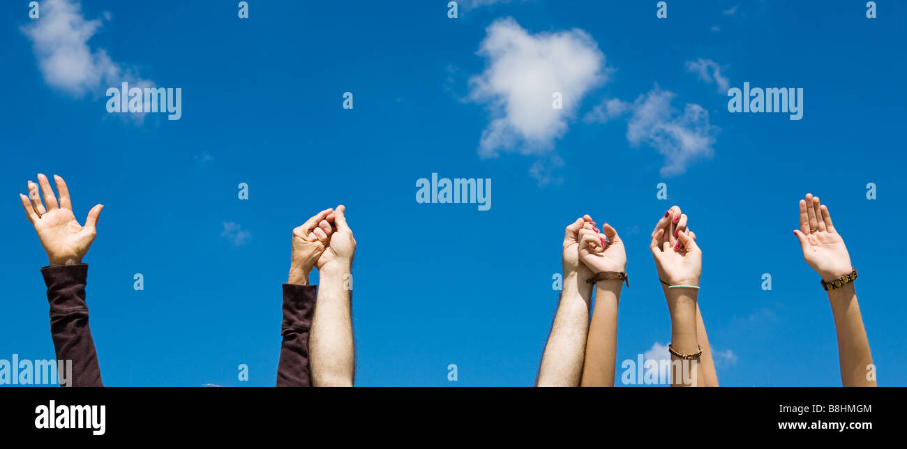 Hands raised and holding eachother against a blue sky Stock Photo - Alamy