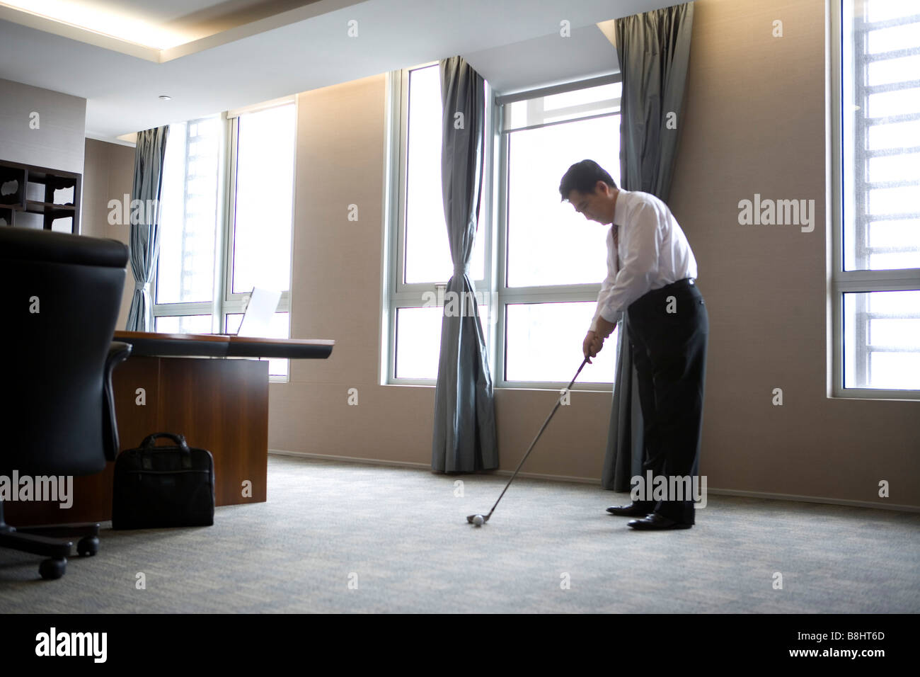 Businessman playing golf in office Stock Photo - Alamy