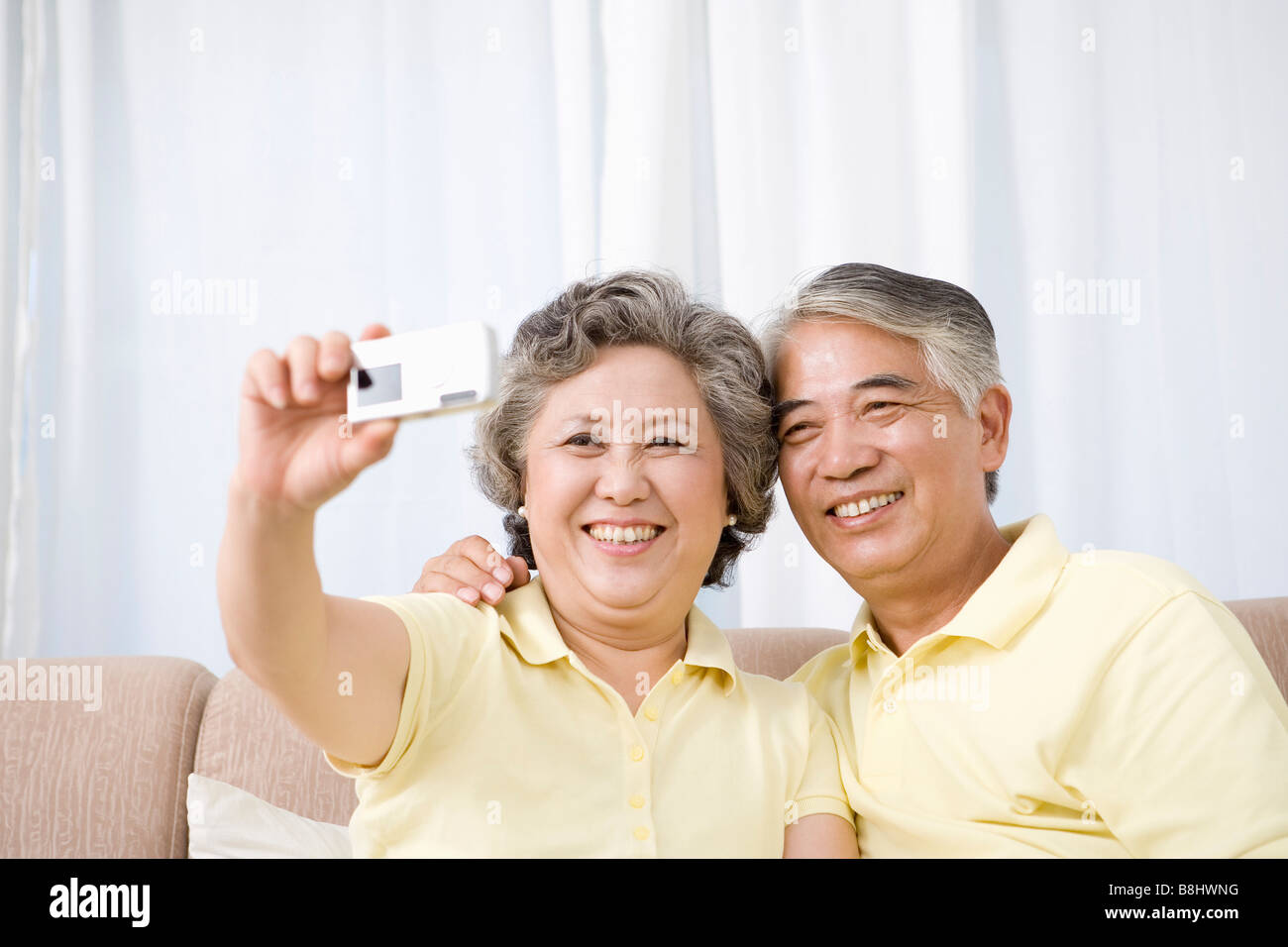 Senior couple taking picture with camera indoors Stock Photo - Alamy