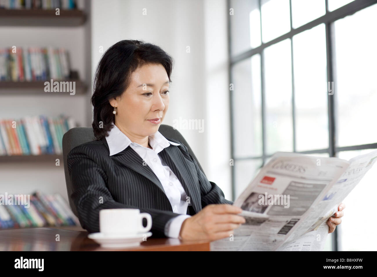 Businesswoman reading newspaper in office Stock Photo - Alamy