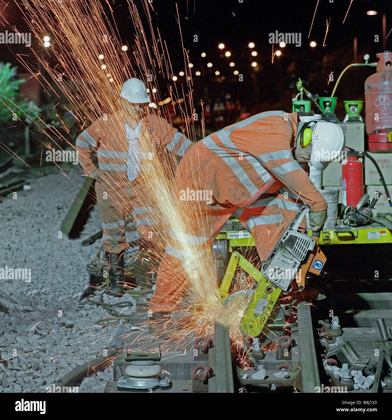 Contractor working at night using abrasive disc machine cuts lengths of ...
