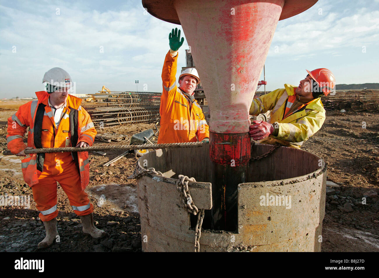 Contractors pouring concrete into excavated deep foundation pile after ...