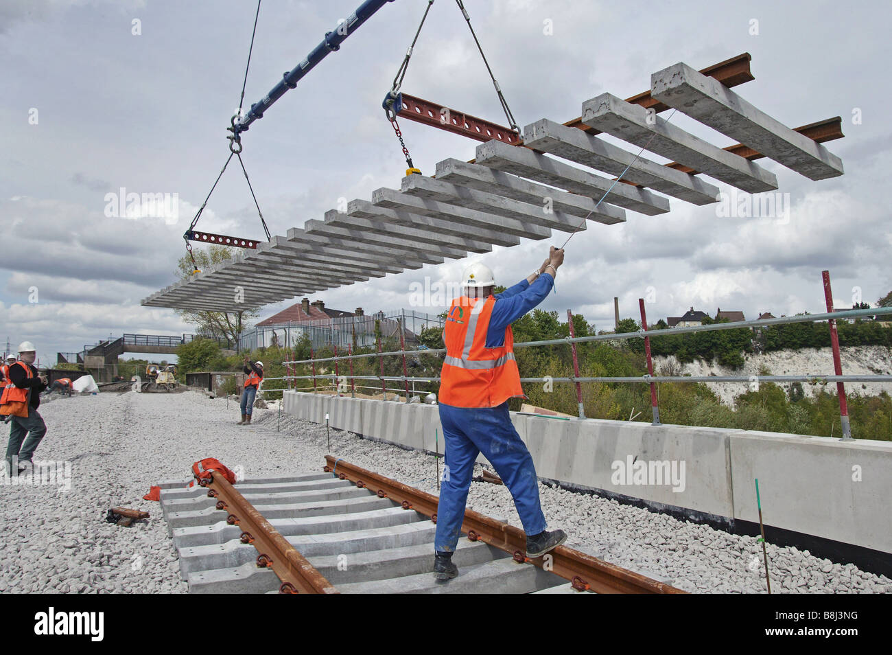 Rail contractors lowering a section of prefabricated track with rails ...