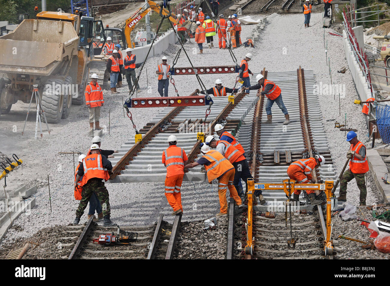 Rail contractors lowering a section of prefabricated track with rails ...