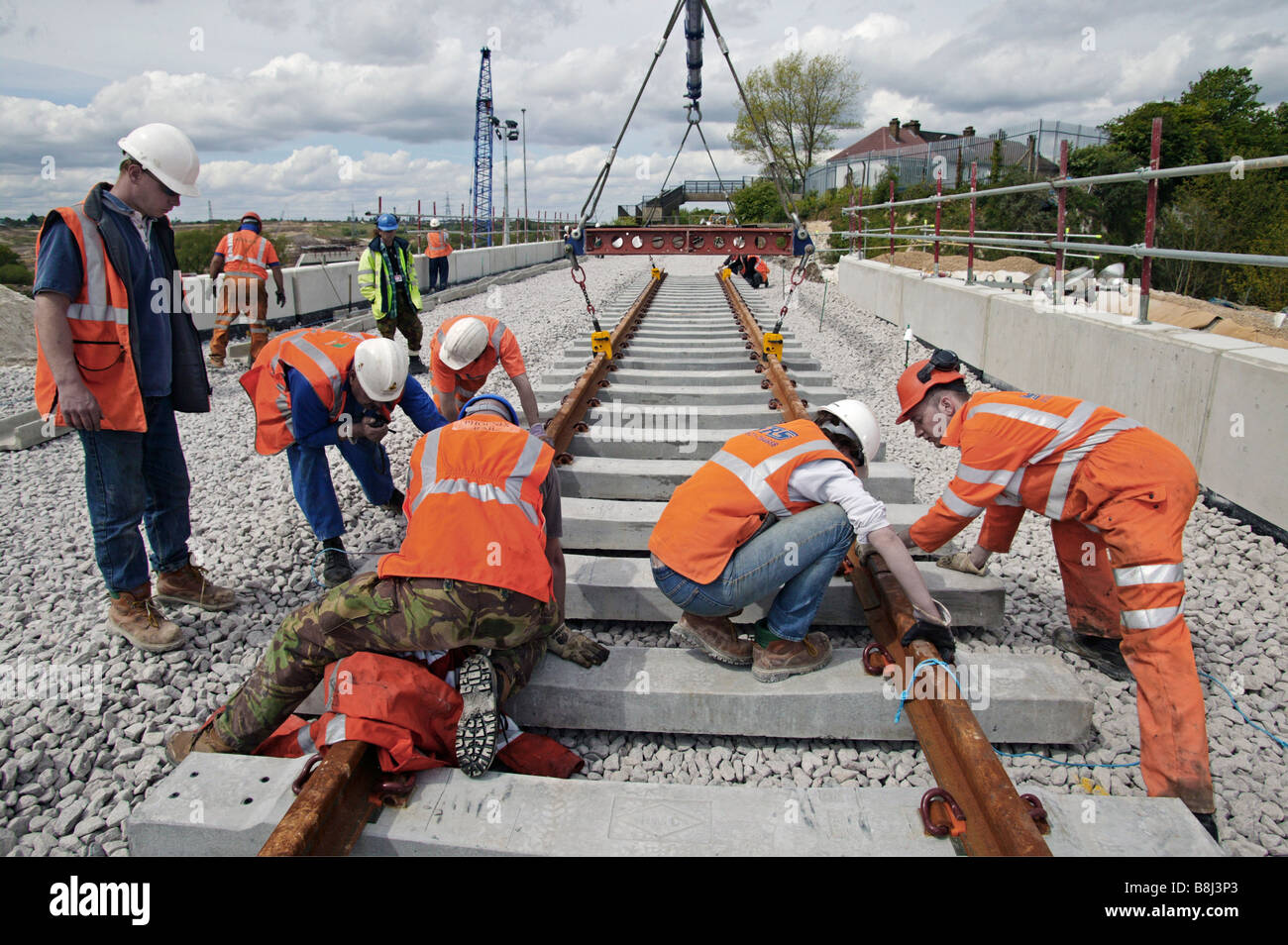 Rail contractors lowering a section of prefabricated track with rails ...