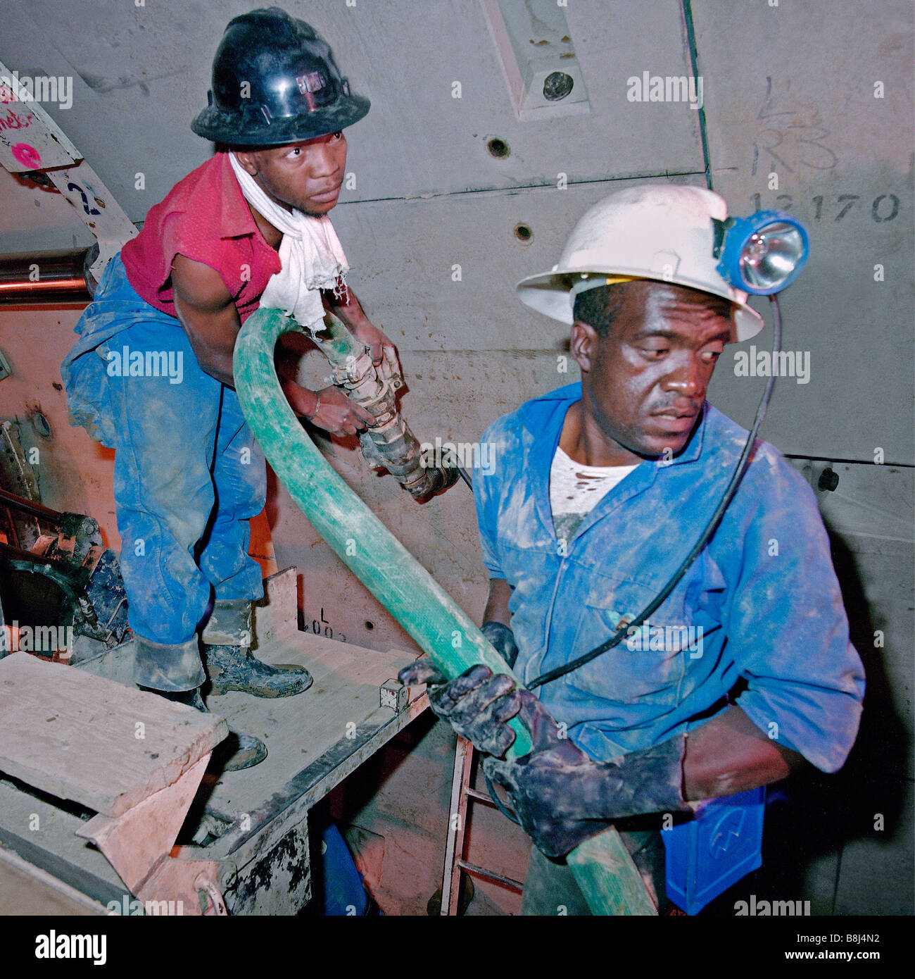 Workers grout concrete tunnel wall support segments in delivery tunnel ...