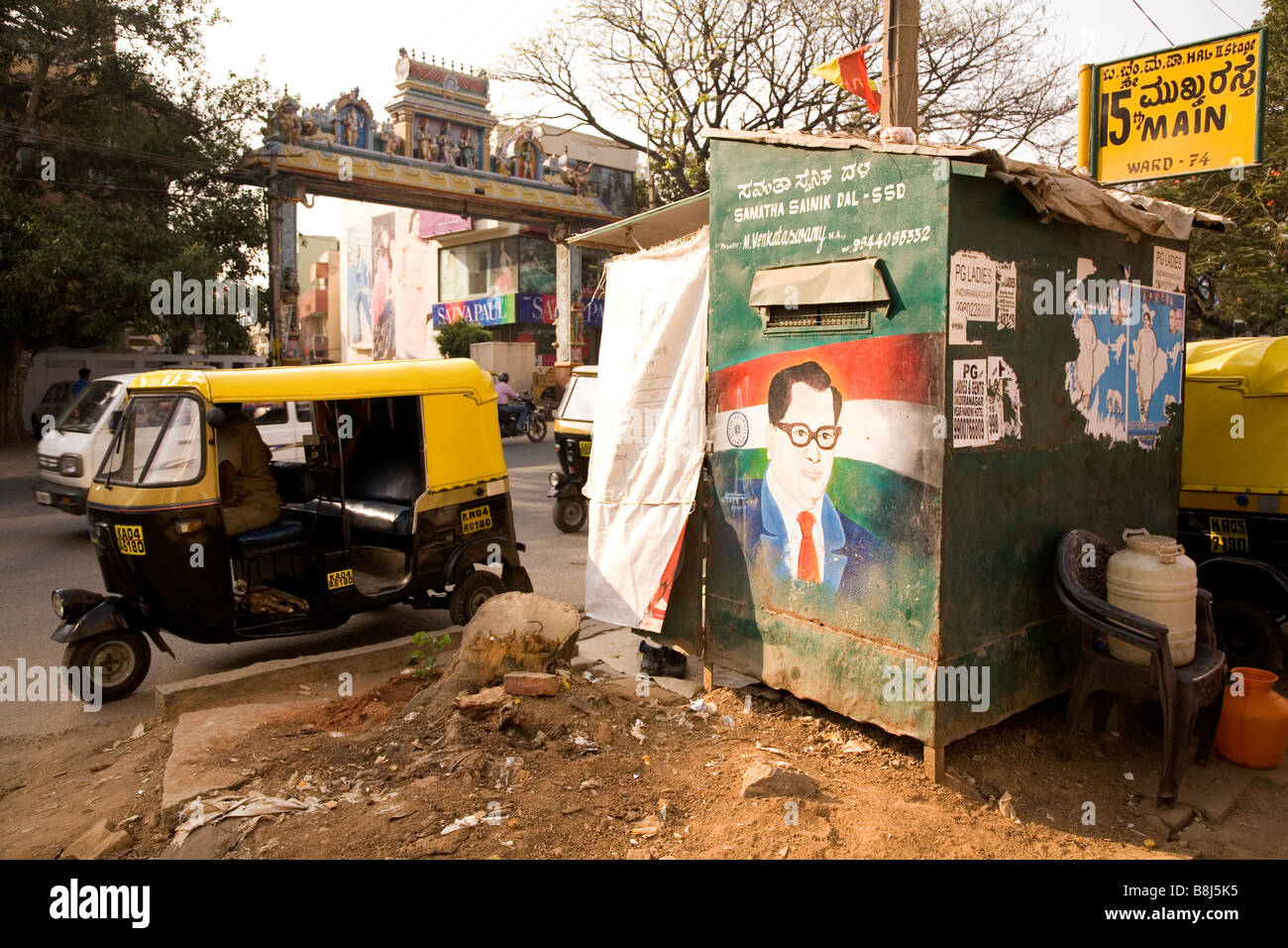 A street scene in Bangalore, India. A rickshaw stands next to a cobbler ...