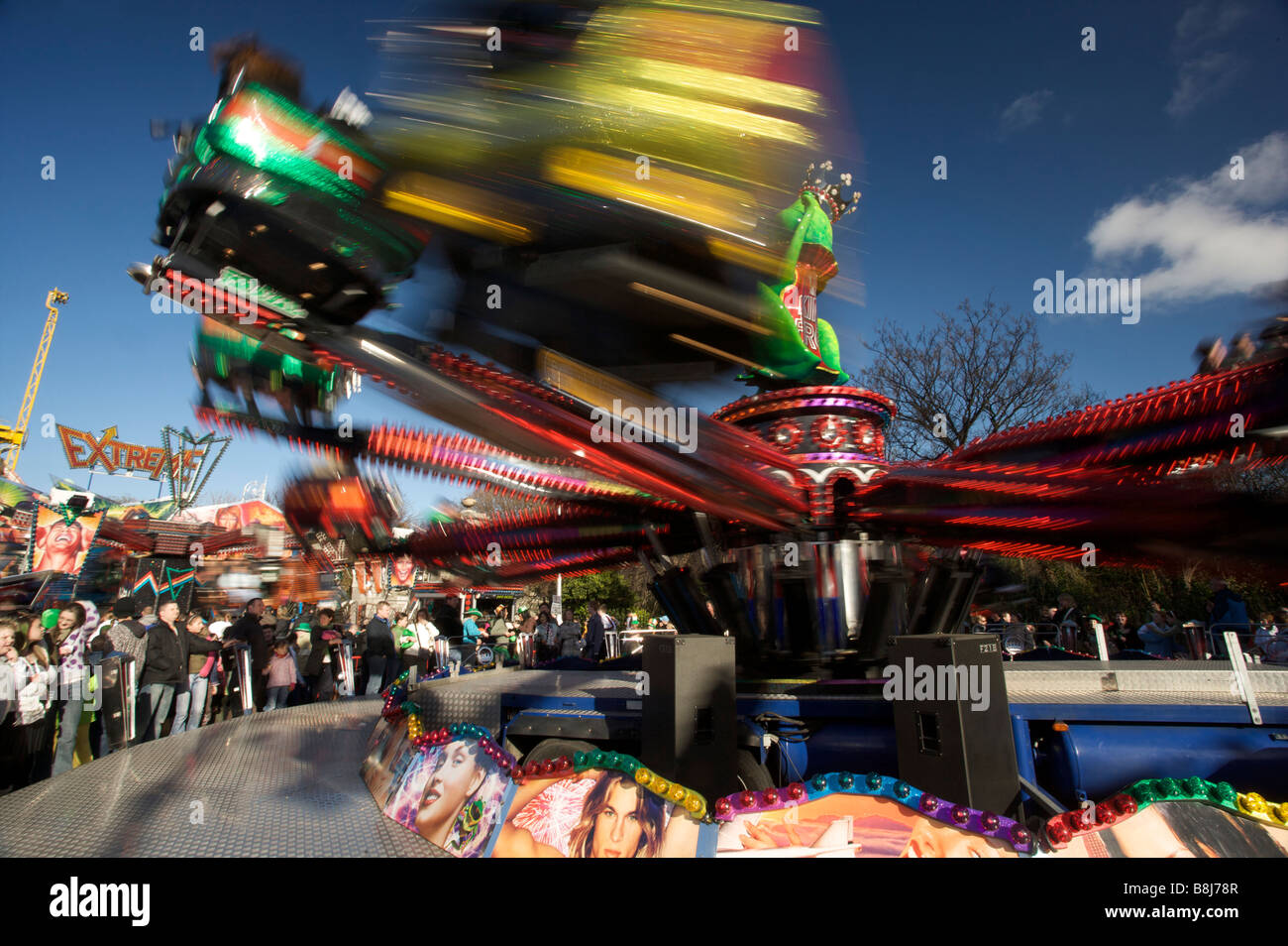 People riding an amusement park ride in bright sunshine are riding so ...