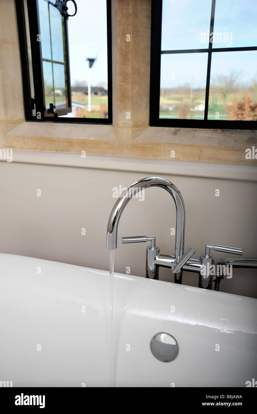 A MODERN LUXURY BATH WITH A MIXER TAP FILLING WITH WATER Stock Photo ...