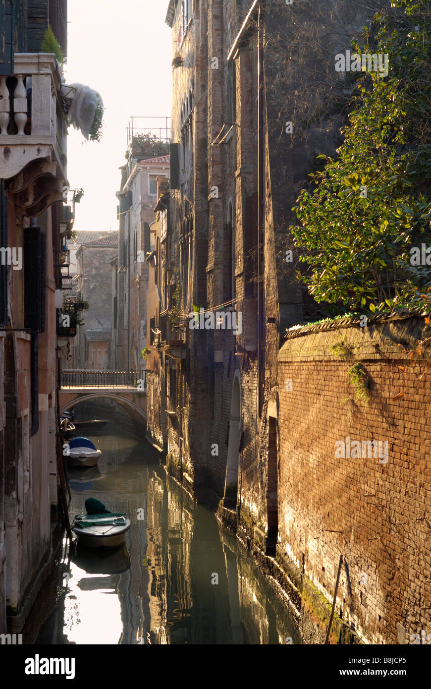 An empty Venetian backwater canal with reflections of late afternoon ...