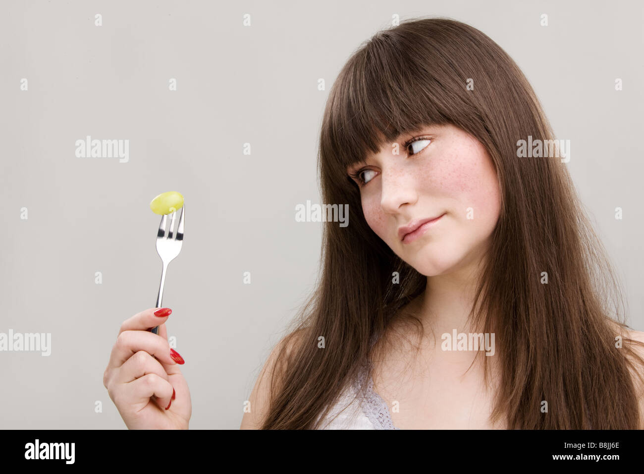 Portrait of young girl holding fork with a grape Stock Photo - Alamy