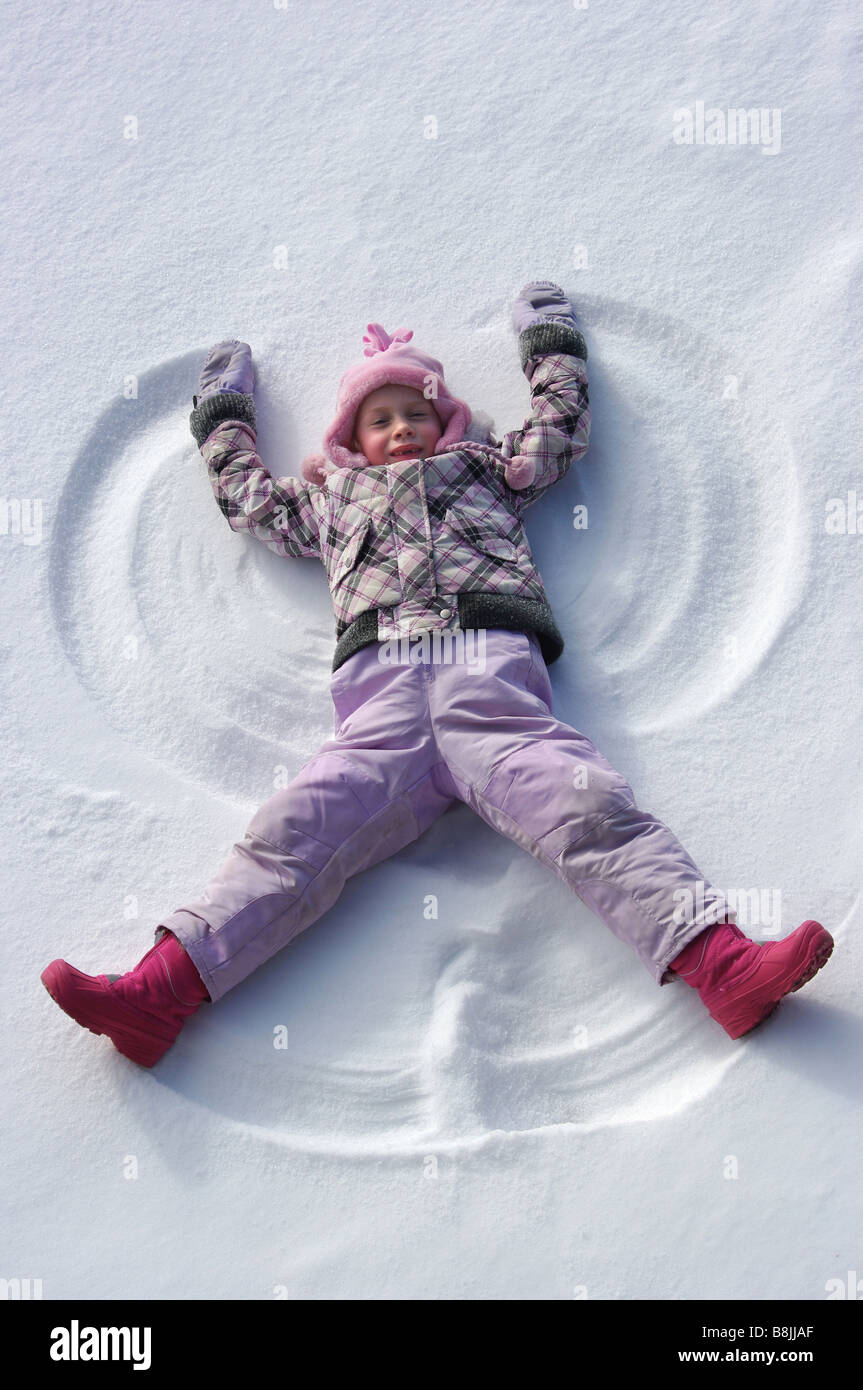 With powder snowing on the ground, a little girl playing around makes ...