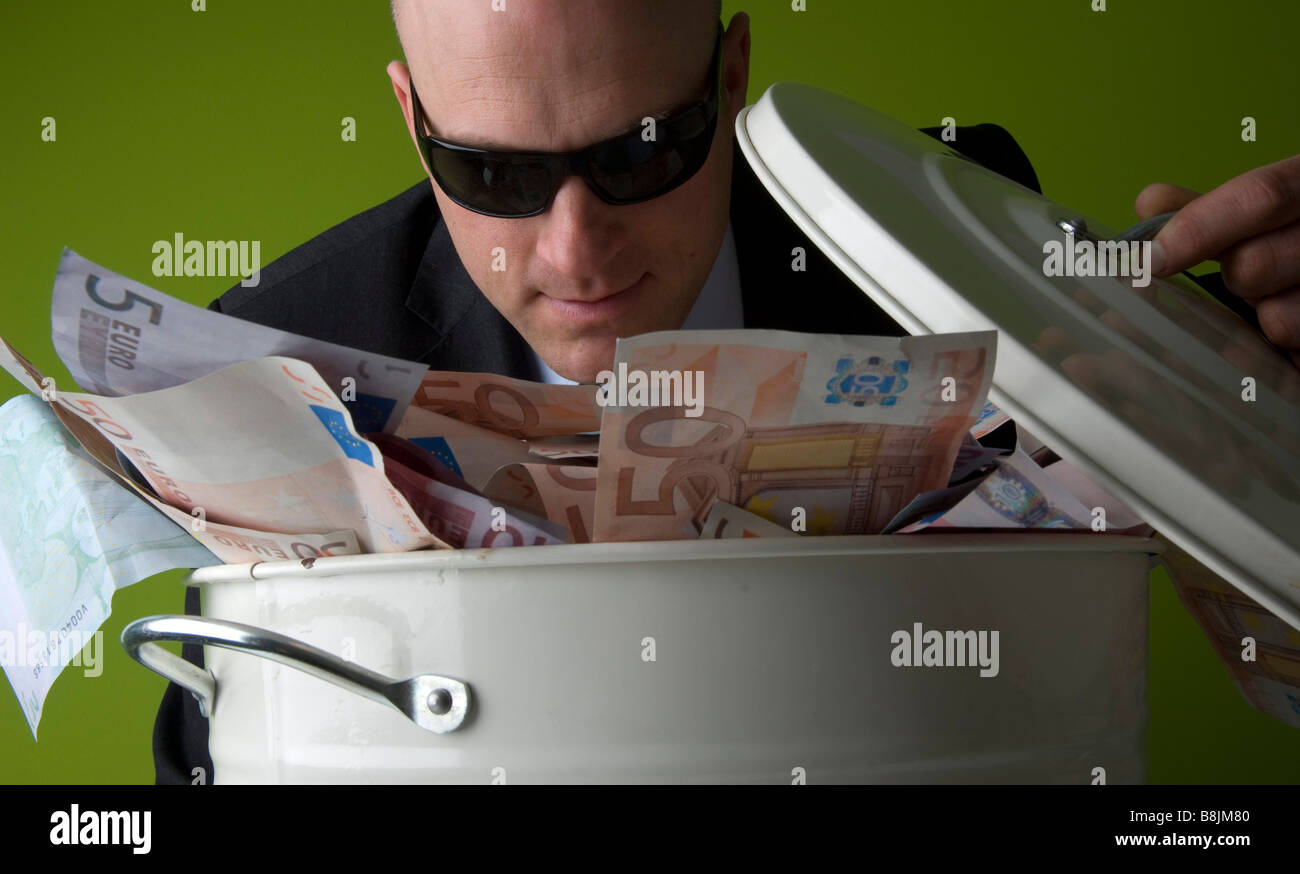 Man in suit with dustbin full of Euro money Stock Photo - Alamy