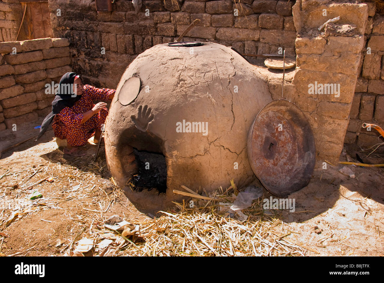 Egyptian woman finishes traditional sun-baked bread in an oven Stock ...