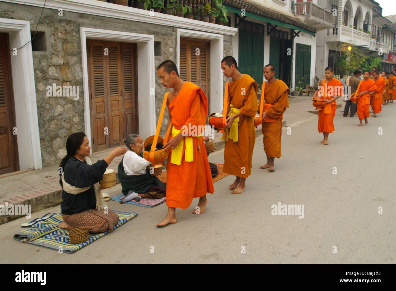 Buddhist monks collecting food from the devout at dawn, Luang Prabang ...