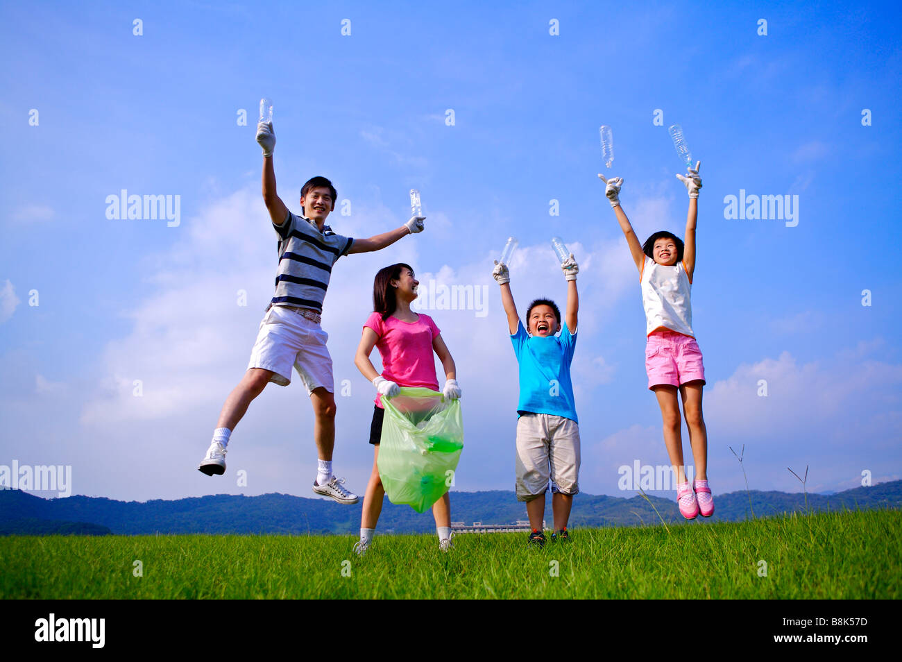 Young family with two children jumping frow the lawn and holding ...
