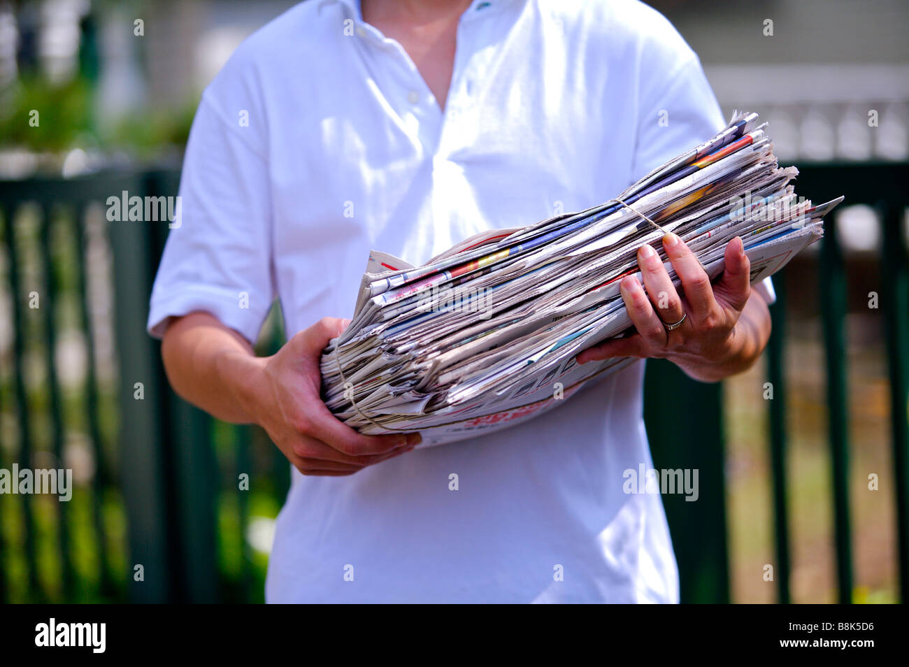 Man holding a stack of newspaper for recycling Stock Photo - Alamy