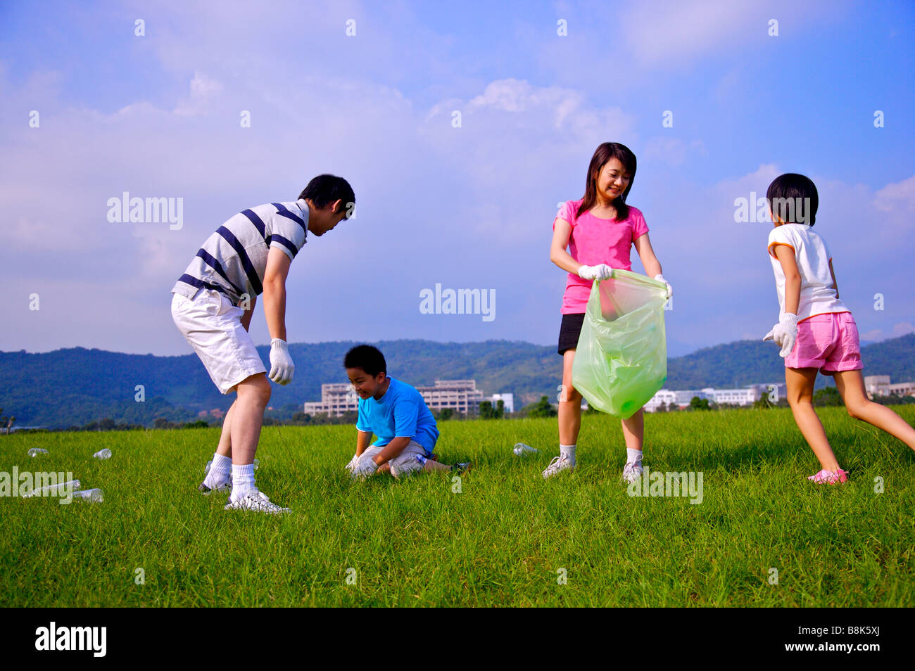 Young family with two children picking empty bottles up and putting ...