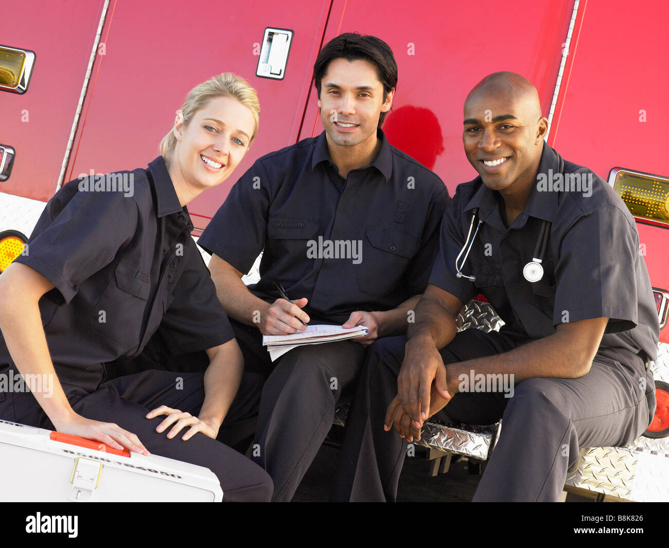 Three paramedics chatting and doing paperwork, sitting by their ...