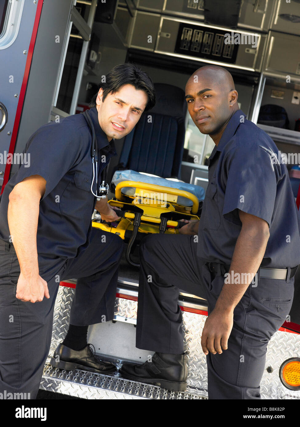 Two paramedics cheerfully removing empty gurney from ambulance Stock ...