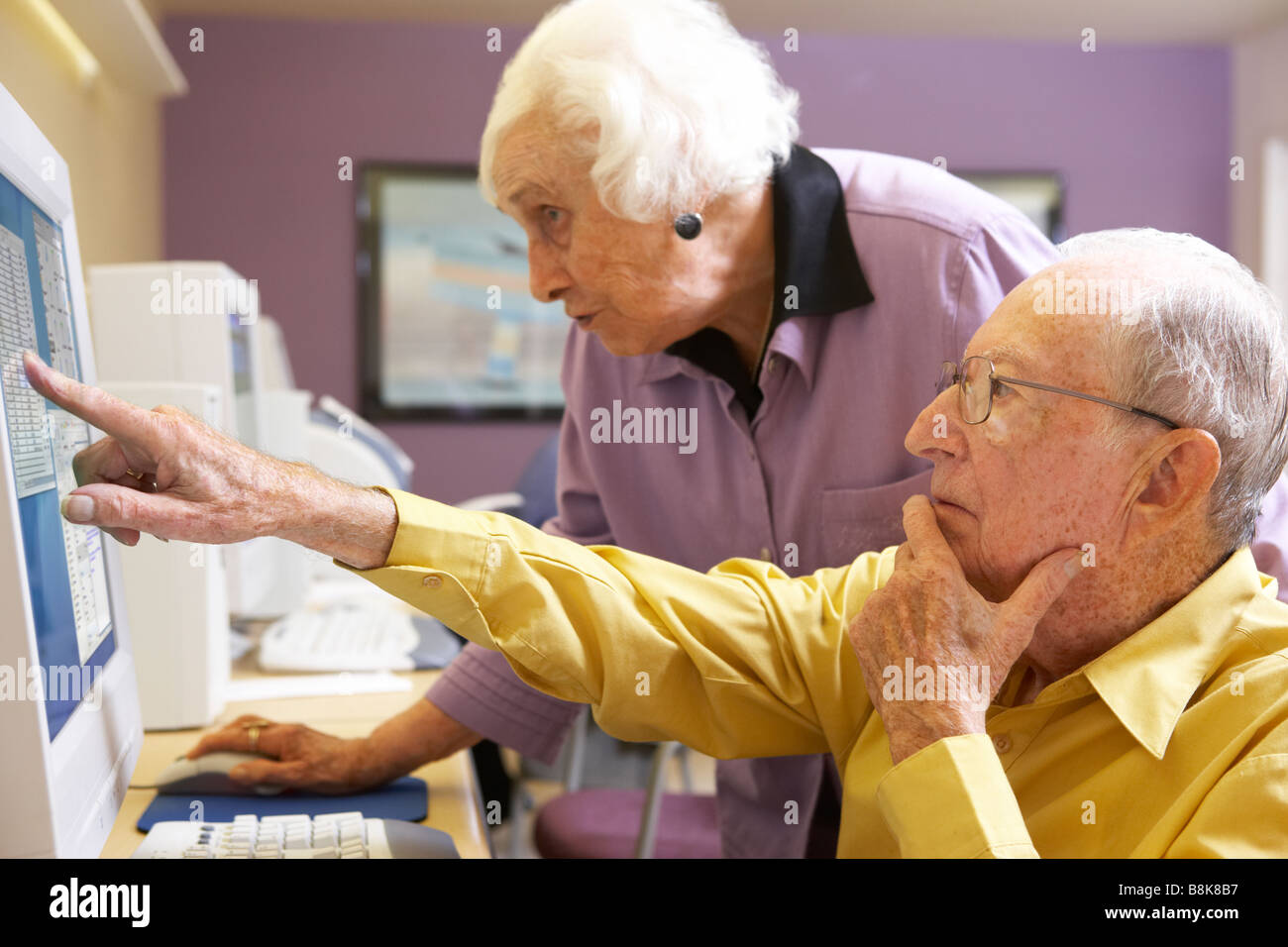 Senior woman helping senior man use computer Stock Photo - Alamy