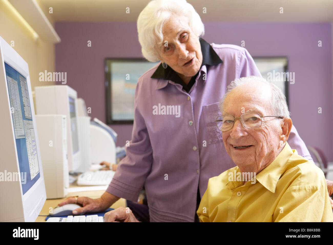 Senior woman helping senior man use computer Stock Photo - Alamy
