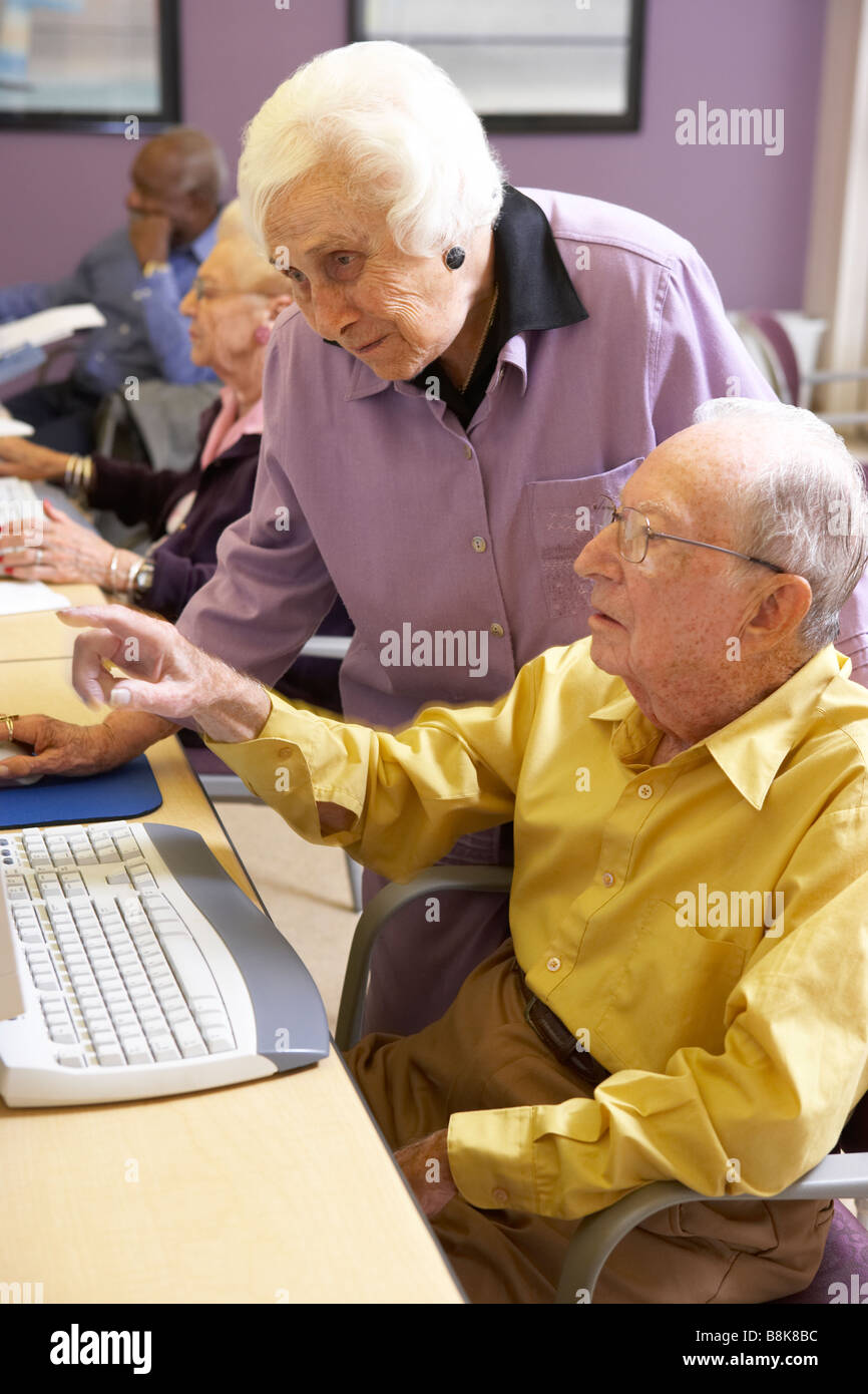 Senior woman helping senior man use computer Stock Photo - Alamy