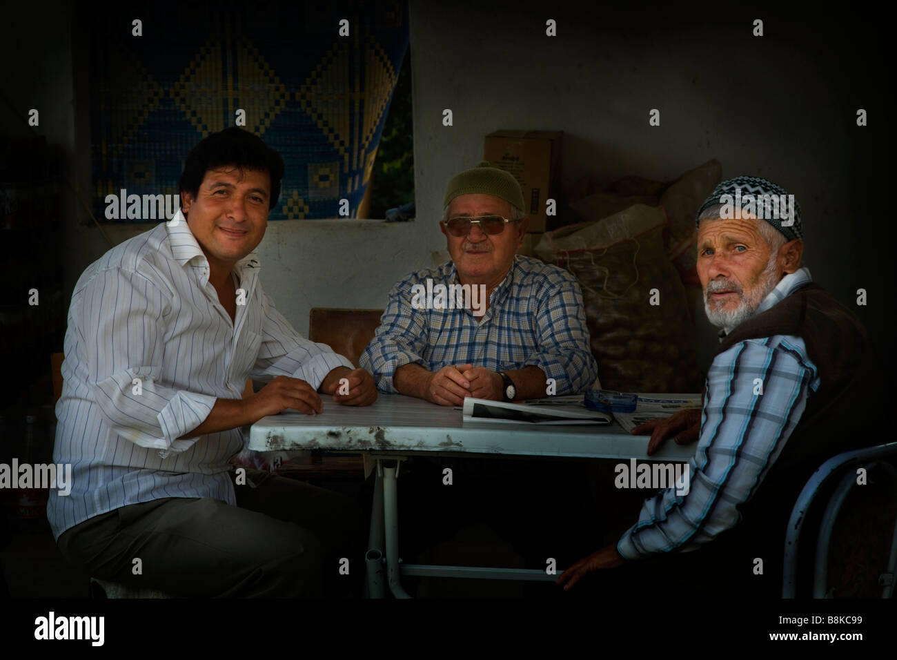 three Turkish men sat at a table in an outdoor pavement cafe in Turkey ...