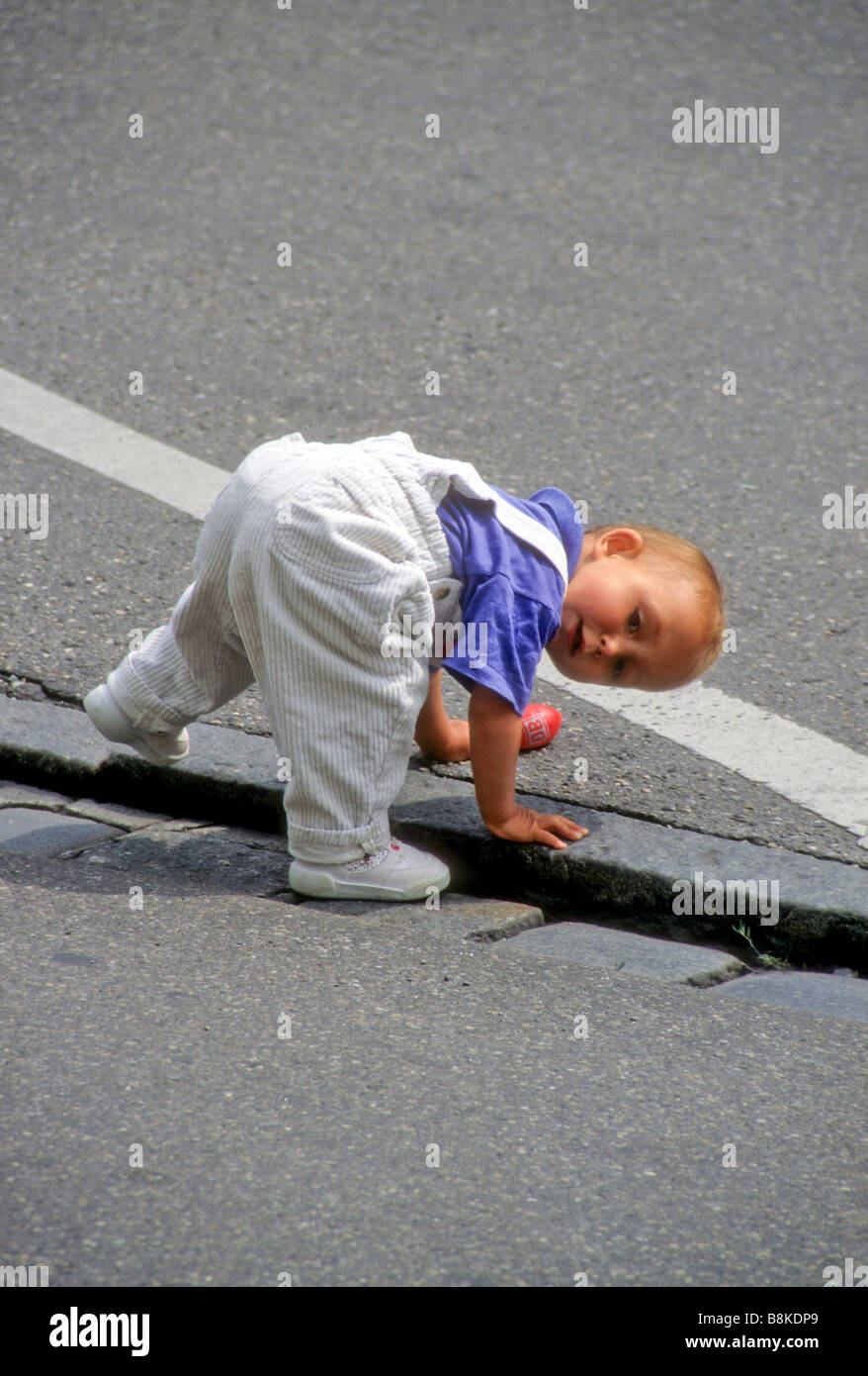 German toddler crawls down curb Stock Photo - Alamy