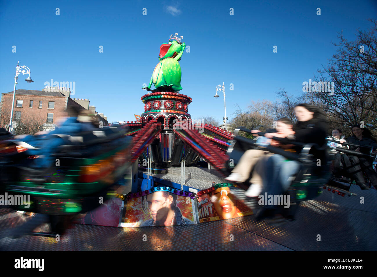 People riding an amusement park ride in bright sunshine are riding so ...