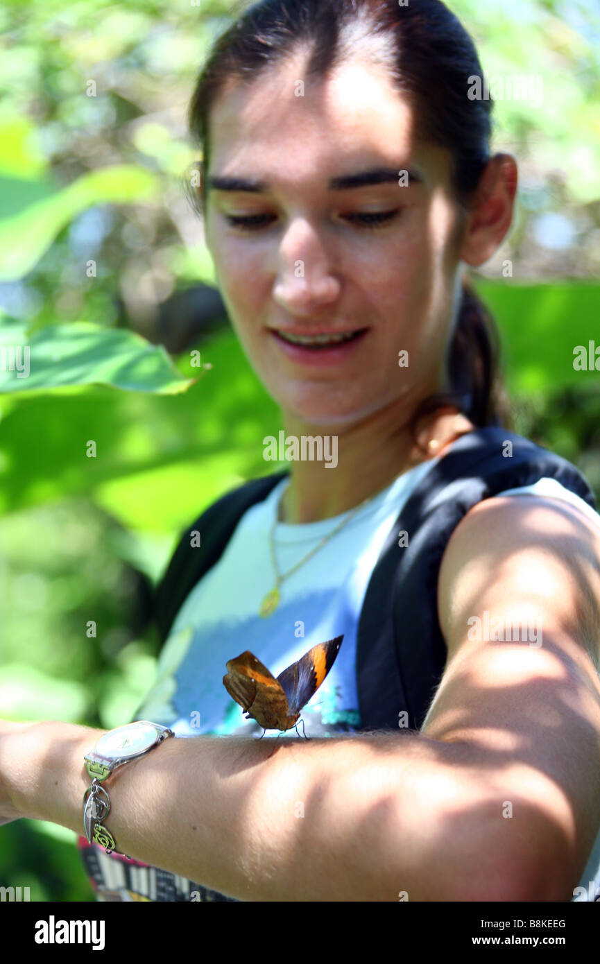 A woman looking at a butterfly on her arm in the butterfly garden on ...