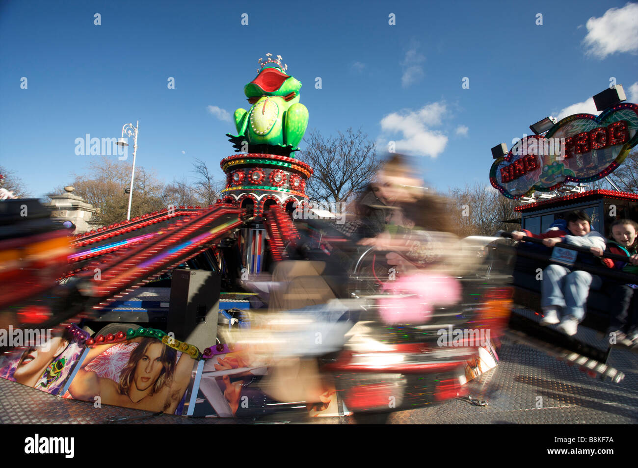 People riding an amusement park ride in bright sunshine are riding so ...
