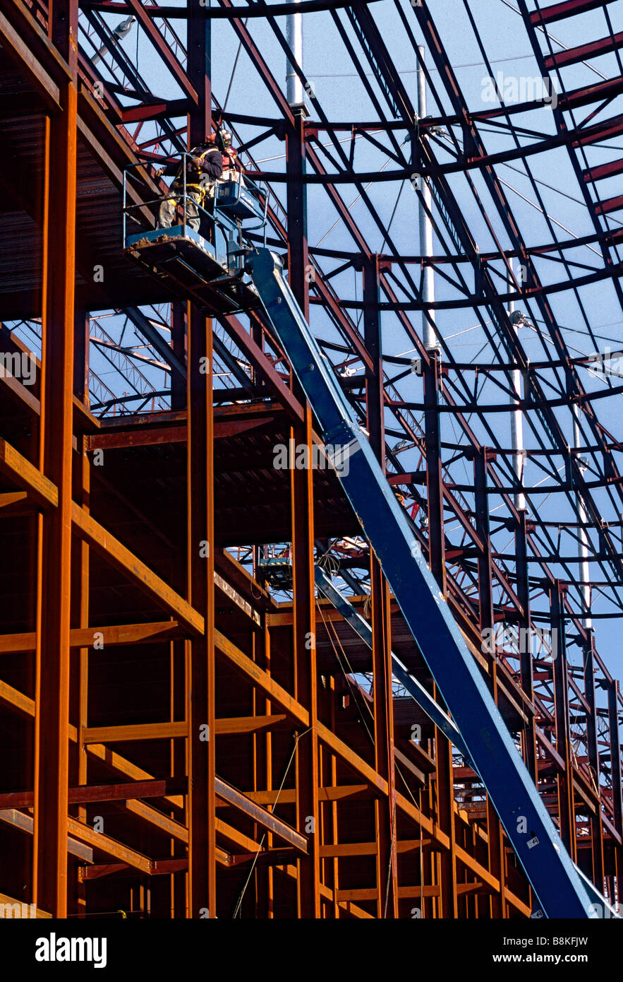 Construction workers on aerial lift working on steel beam framework ...