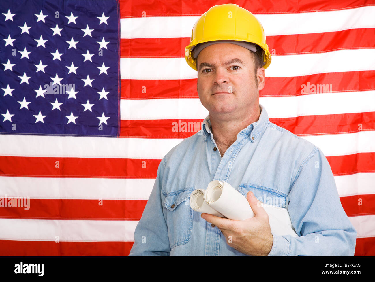 Construction worker with blueprints in front of an American flag ...