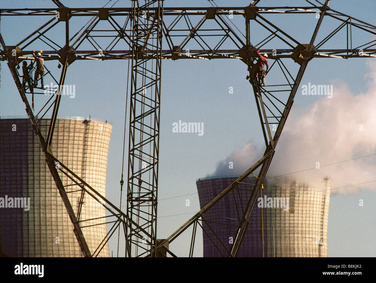 Workers constructing high tension power line towers at electric power ...
