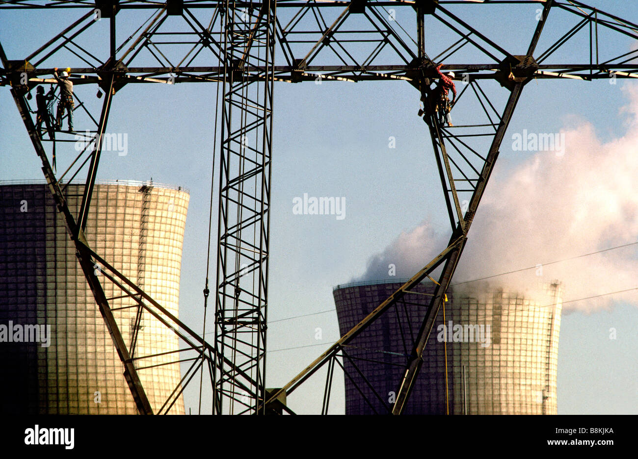 Workers constructing high tension power line towers at electric power ...