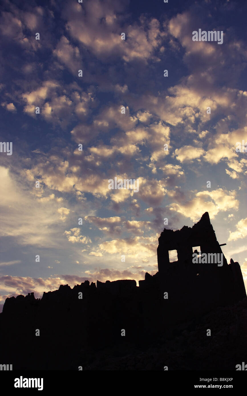 Deserted Kasbah town at dusk. A partially collapsed mud built tower in ...